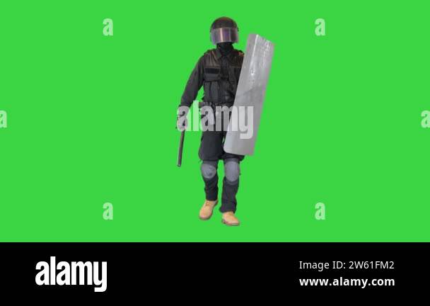 Heavily armored policeman with a shield and a baton walking on a Green ...