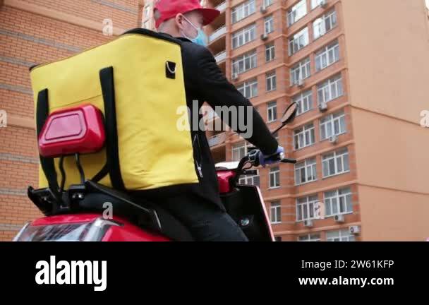 A courier on a moped appears in the frame, stops and checks the ...