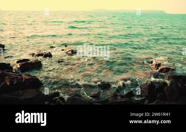 Dark and moody cinematic scene of waves crashing into rocks in slow ...