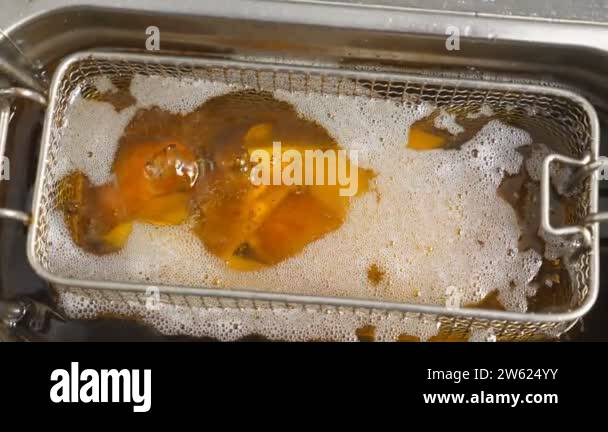 Slices of potatoes rustic is frying in hot boiling oil at cuisine ...