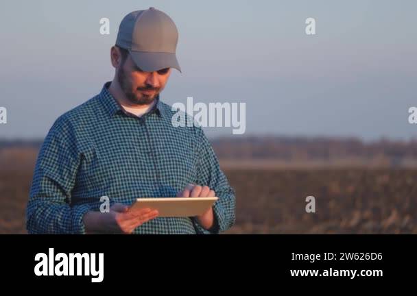 a kind farmer smiles, an agronomist in a plowed field works in a tablet ...