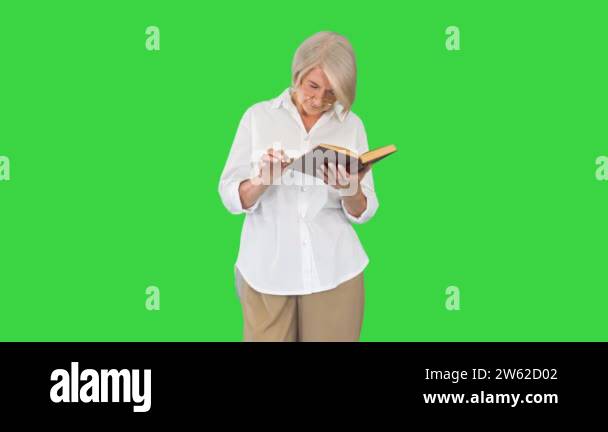 Senior lady woman reading old book with glasses on a Green Screen ...
