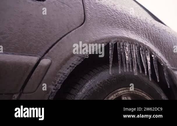 Icy car after an icy rain. Icicles hang on the mirror and arches of the ...