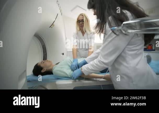 Two radiologists inserts an intravenous catheter to inject contrast to ...
