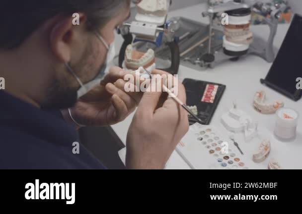 A dentist creates a model of a jaw prosthesis and ceramic teeth in the ...
