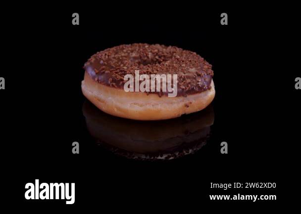 Donut with chocolate icing rotating on a black background. Sweet ...