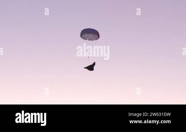 A military reconnaissance drone parachutes into the mountains at sunset ...