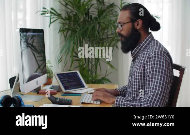 Lockdown of young Indian programmer sitting at computer and typing ...