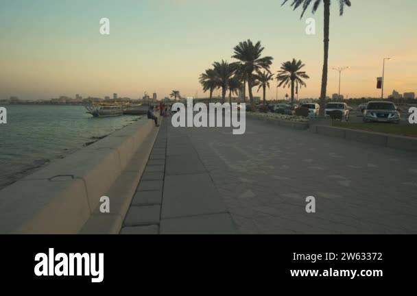 Doha corniche sunset zooming in and panning shot showing people walking ...