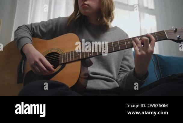 The girl runs the fingers of her right hand along the strings several ...