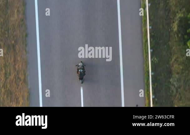 Top view to motorcyclist races his motorcycle on highway at sunny day ...