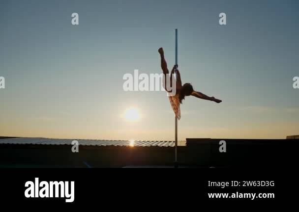 pole dance. silhouette. fit female gymnast, in beige leotard, performs ...