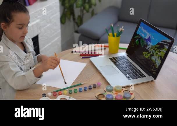 Young girl spending a time drawing using online lessons on laptop ...