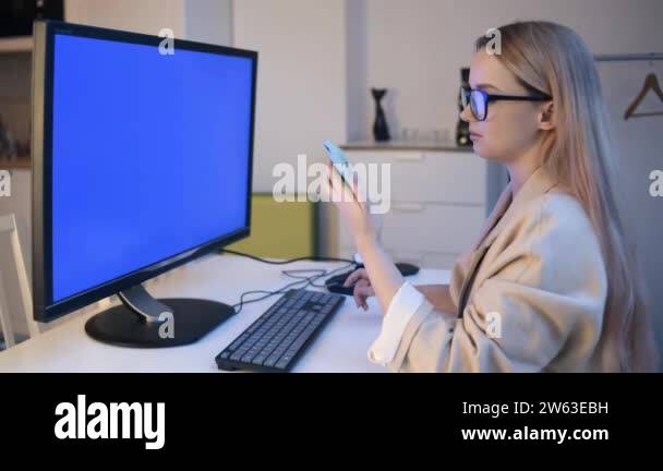 The girl looks into the green screen of the monitor.Girl works at home ...