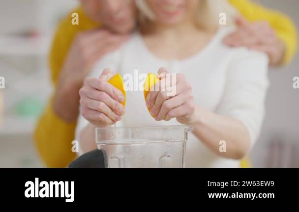 Close-up of female hands squeezing lemon in blender with blurred ...