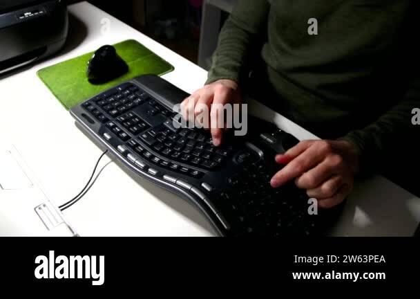 European man slow typing with two finger system on ergonomic keyboard ...