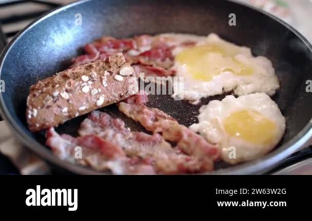Tasty steaming english breakfast on gas stove, crispy bacon strips, two ...