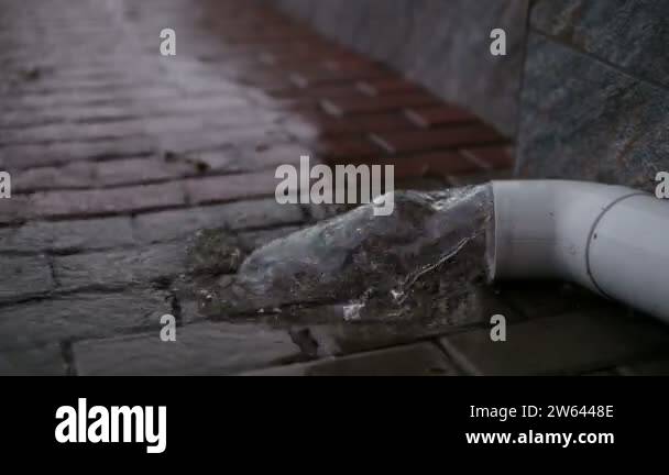 Strong rain water flowing out from rain drain pipe on a building wall ...