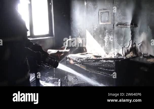 Firefighter Puts out burning furniture in a room in an apartment by a ...