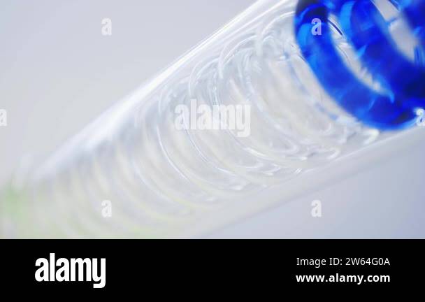 Glass big test tube with canister inside. Blue fluidity flows through ...