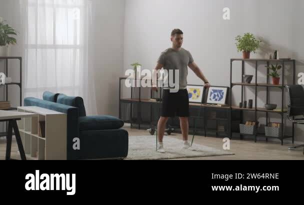 athletic man is training at home, using elastic bands for strength ...