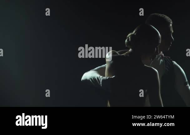 Couple is dancing fast rhythmic tango dance in dark studio with bright ...