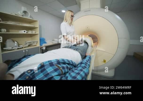 Woman doctor makes knee-joint MRI scanning. Young man patient on ...