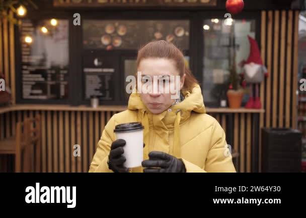 Young woman drinking coffee in a street cafe, frosty morning before ...