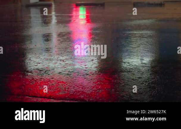 Slow motion rain drops falling into puddle on asphalt at night. Big ...