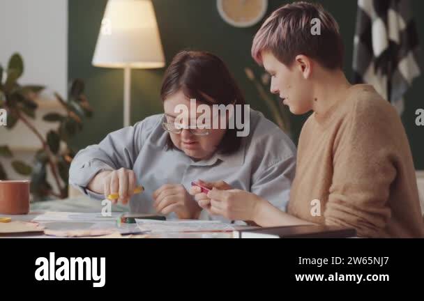 Adult Caucasian man with Down syndrome and female teacher drawing on ...