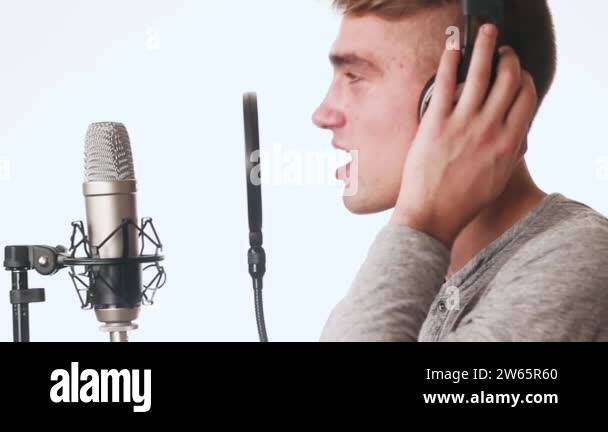 Handsome guy sings in a microphone standing studio headphones ...