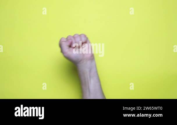 Clenched fist hand raises up in air on yellow background - sign of ...