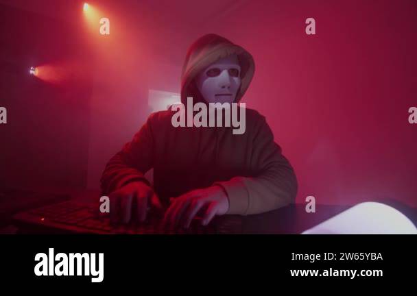 Anonymous person in a white mask works on the computer, inputs code ...