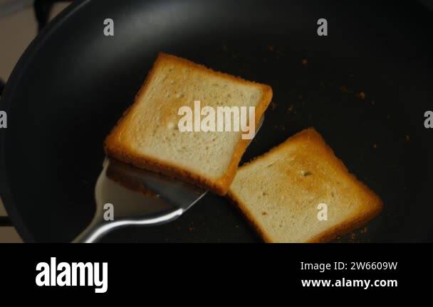 Two slices of toasts cooked in a pan on the stove and tossed over ...
