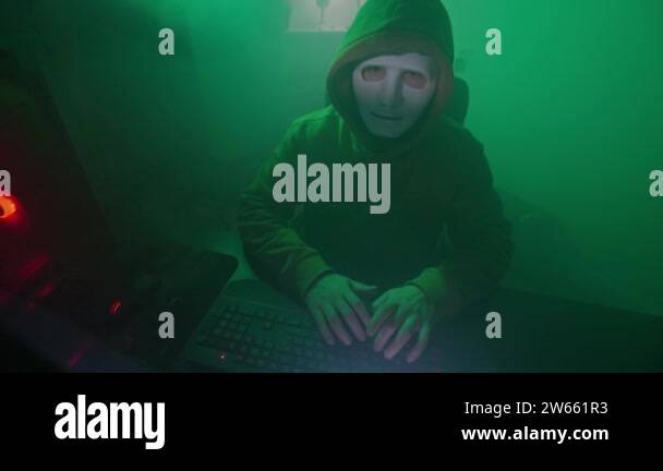 Anonymous person in a white mask works on the computer, inputs code ...