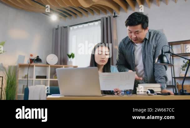 Attractive skilled modern asian father standing near his daughter and helping with university ...