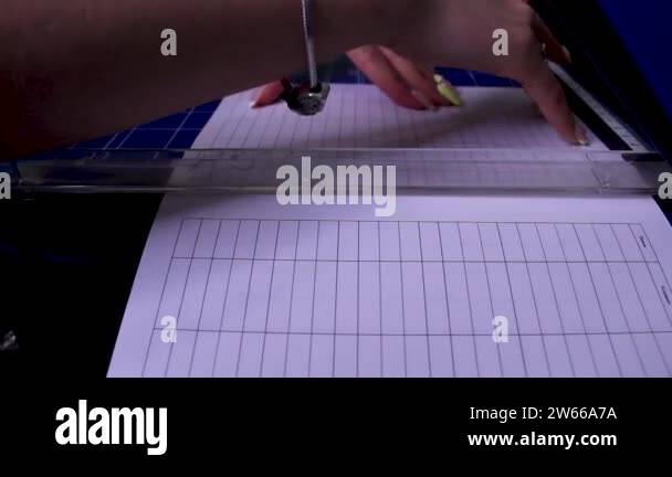 Female hands cutting paper sheet with small manual guillotine. Arts and ...