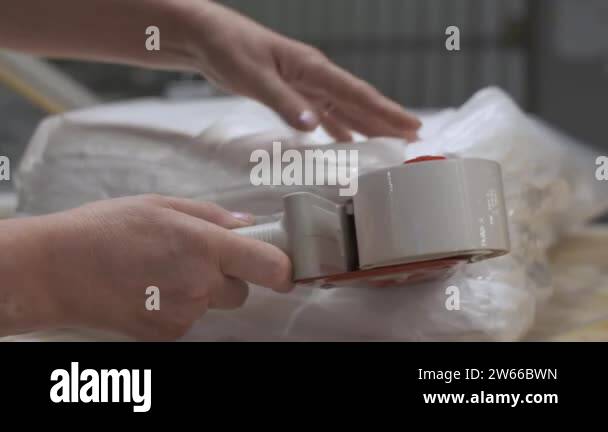 Textile worker at her workplace, hands pack the finished products of ...