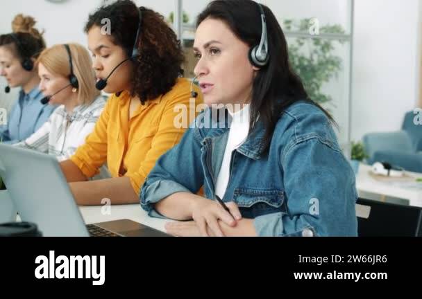 Multiracial group of call center employees talking with headset typing ...
