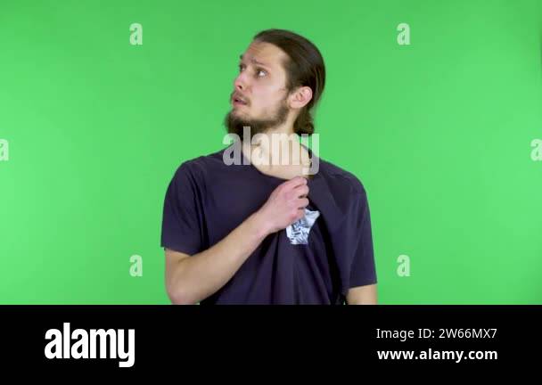 An exhausted young man suffering from heat waves his arms to create the ...