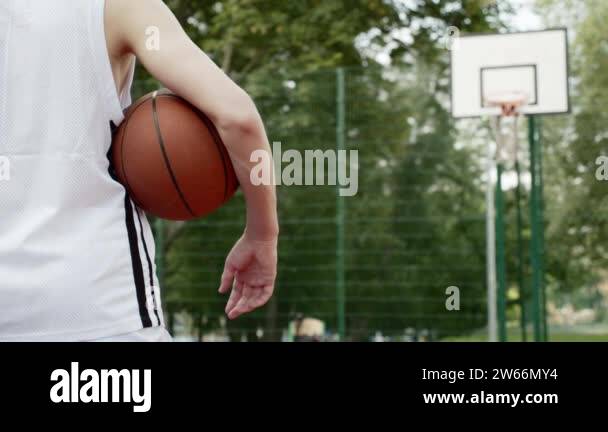Boy standing on a basketball court and holding a basketball under his ...