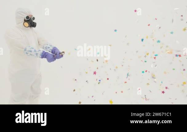 Man in white chemical protection suit and gas mask blows the party ...