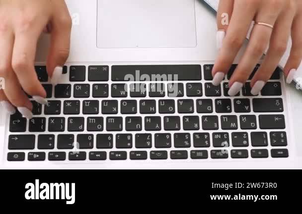 view from top. female fingers type on the laptop keyboard. the girl ...