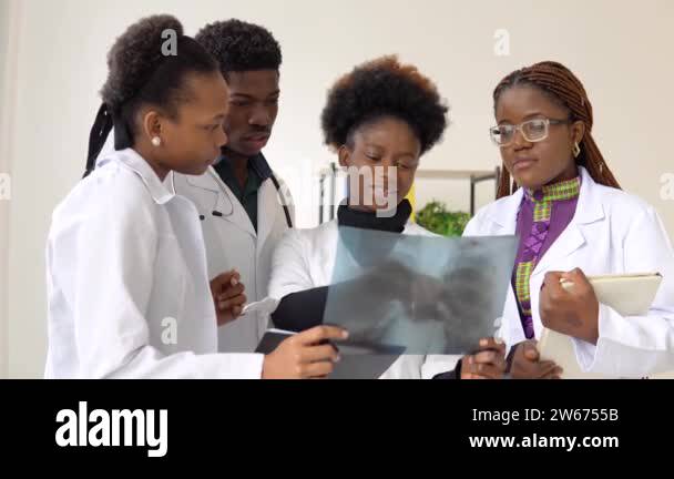 A group of four african american doctors discuss an x-ray scans of a ...