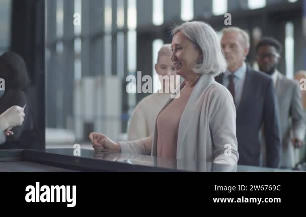 Waist-up shot of multiethnic male and female people standing in queue at check-in counter at ...