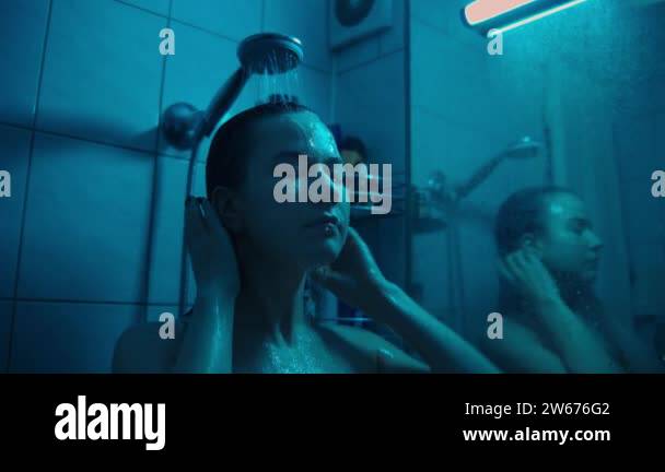 A young girl with long hair washes her hair in the shower. Shower room ...