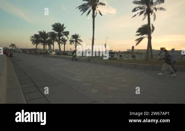 Doha corniche sunset zooming in and panning shot showing people walking ...