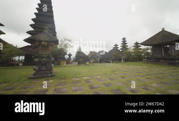 Dolly shot walking across a grassy temple grounds with black stone ...