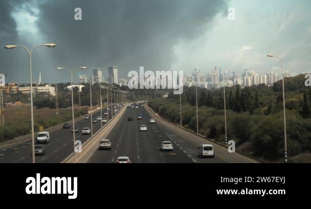 Cars driving on a highway with big grey polluted clouds in the ...