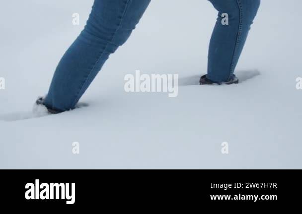 Legs walking on snow with footprints. side view. camera follows the ...
